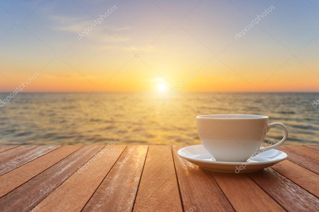 Taza de café blanco en la mesa de madera y vista de la puesta del sol o ...