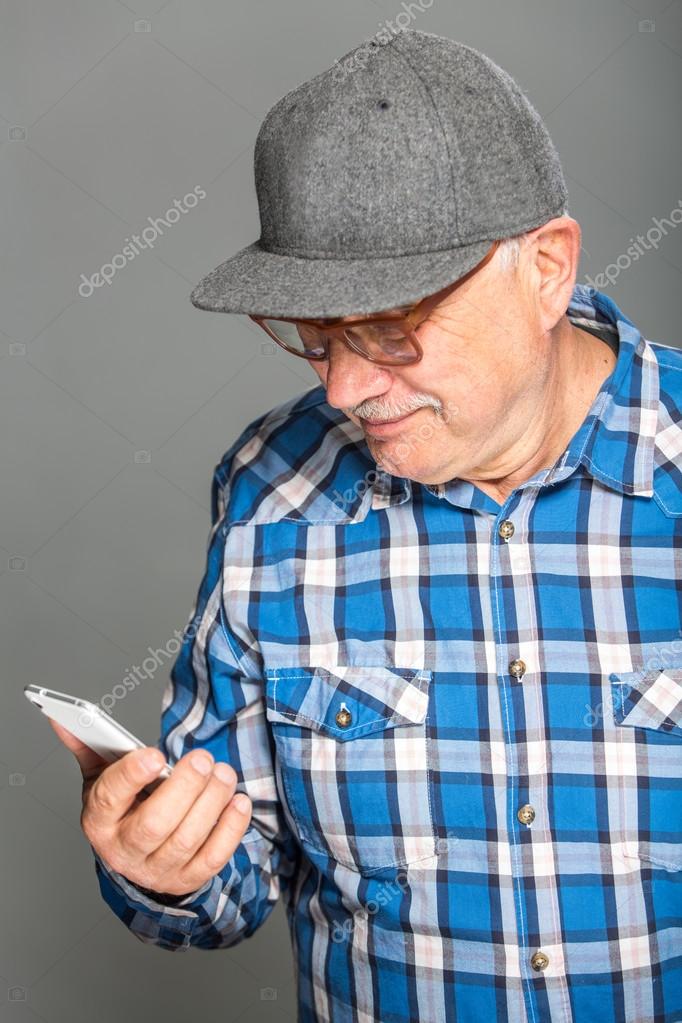 Old active man using mobile phone isolated on grey background Stock ...
