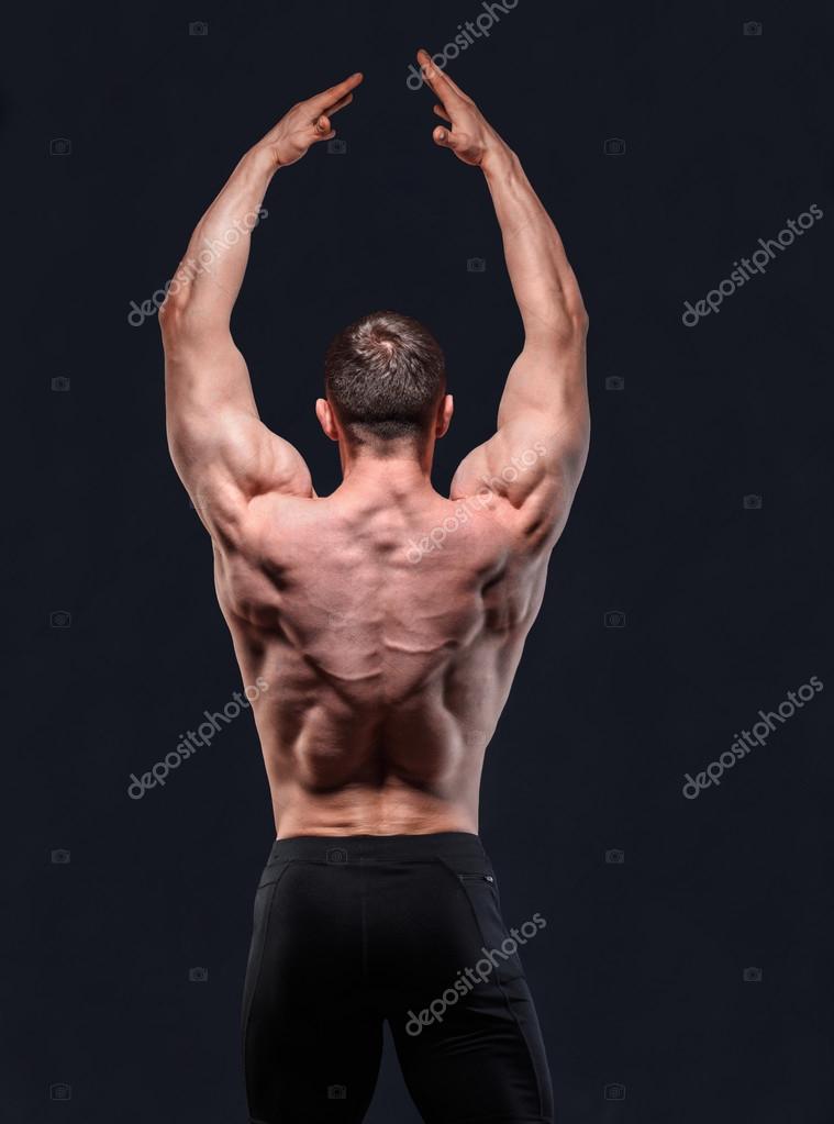 Muscular man in studio show his back with hands held high Stock Photo ...