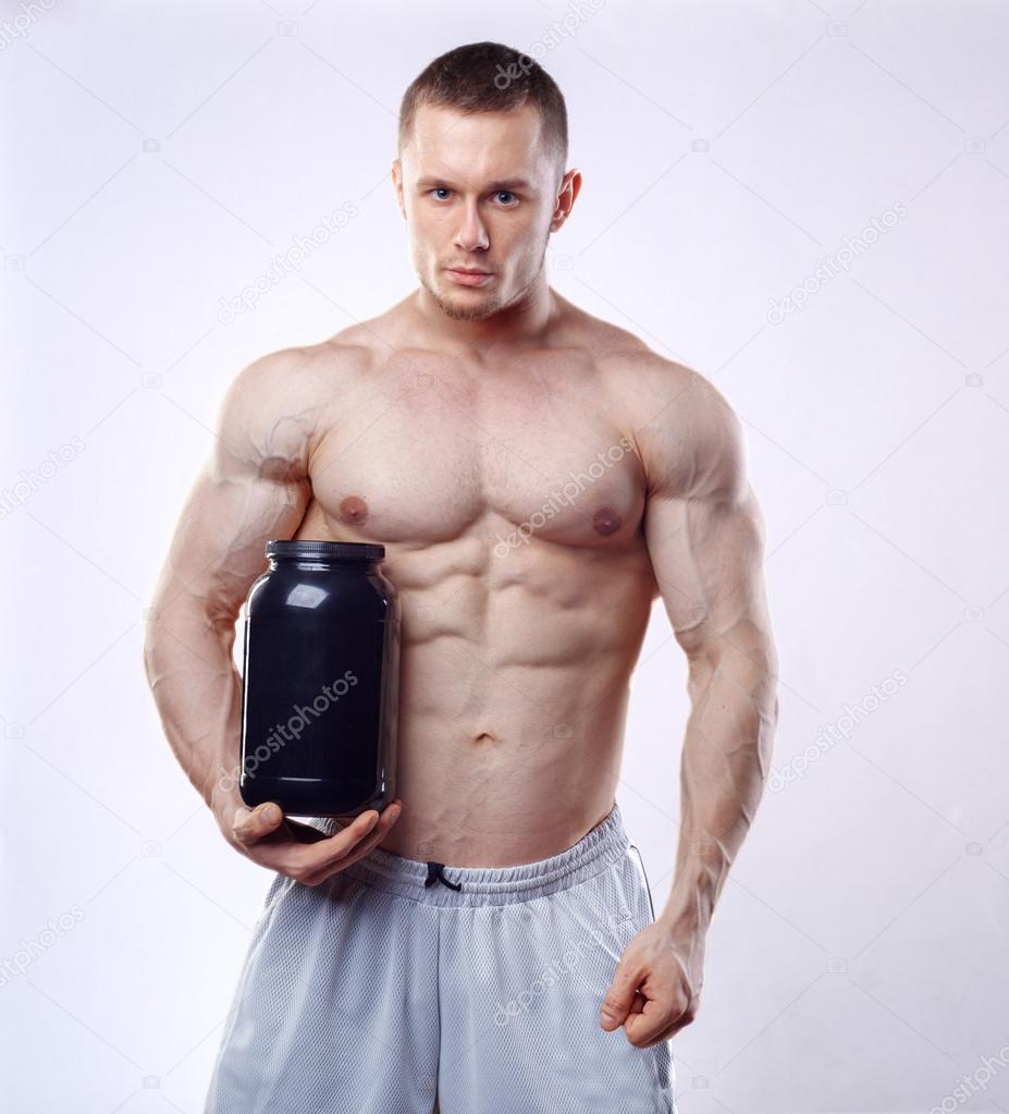 Culturista sosteniendo un frasco de plástico negro con proteína de ...