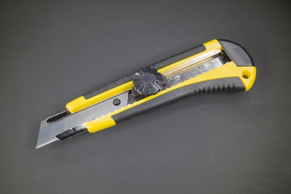 Utility knife with yellow plastic handle and black rubber insert ...