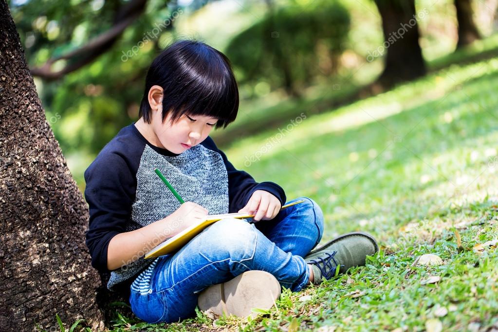 Little asian boy writing book with pencil in the park — Stock Photo ...