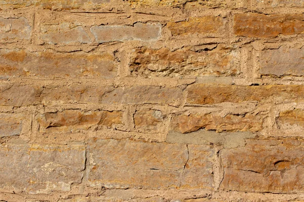 Full frame texture background of an antique golden brown stone wall ...