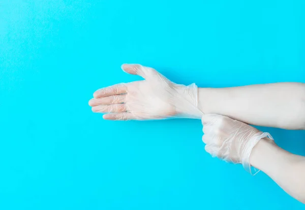 Human hands puting on vinyl disposable gloves above bright blue ...