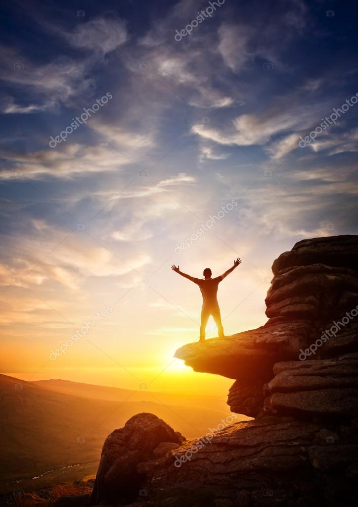 A person reaching up from a high point, set against a sunset — Stock ...