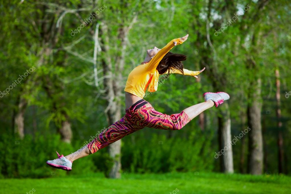 Young beautiful girl doing gymnastic jumps outdoors — Stock Photo ...