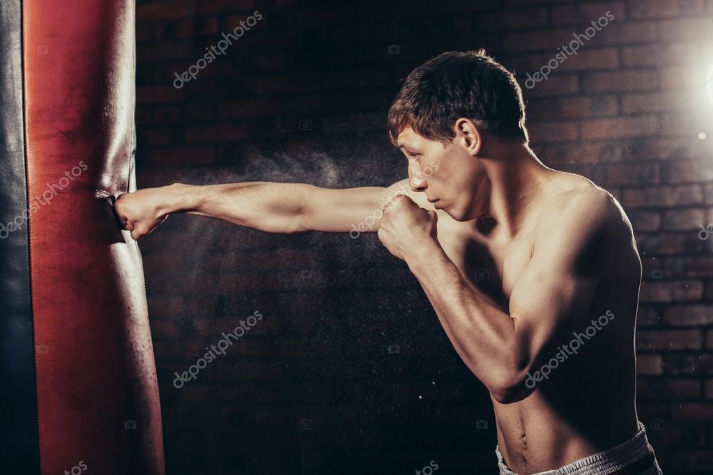 Muscular handsome fighter giving a forceful forward kick during ...