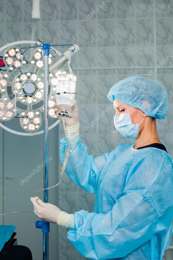 Nurse adjusting infusion bottle with against background of the ...