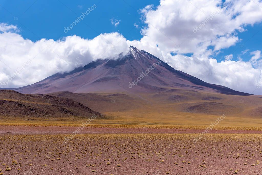 Volcán Licancabur con pico nevado ubicado contra cielo azul nublado en ...