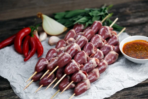 Ready to cook Duck Heart stringed on skewers BBQ with hot sauce and ...
