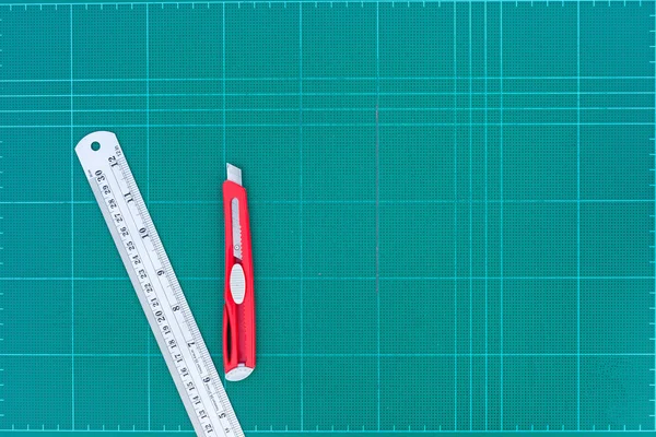A ruler and cutter on green cutting mat - Stock Image - Everypixel