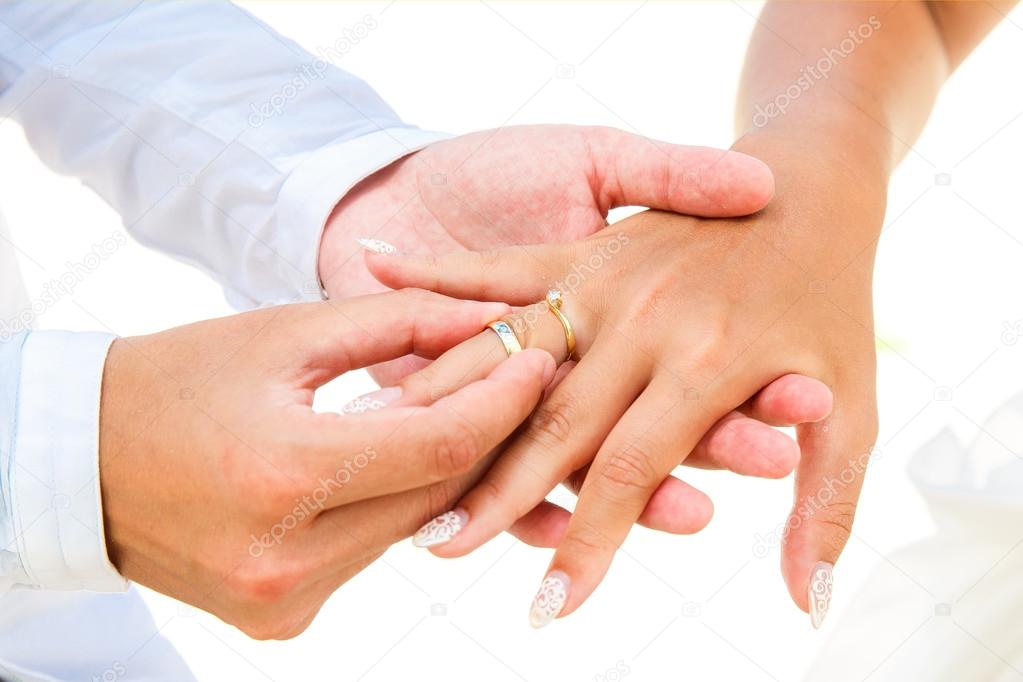 Groom giving an engagement ring to his bride under the arch deco ...