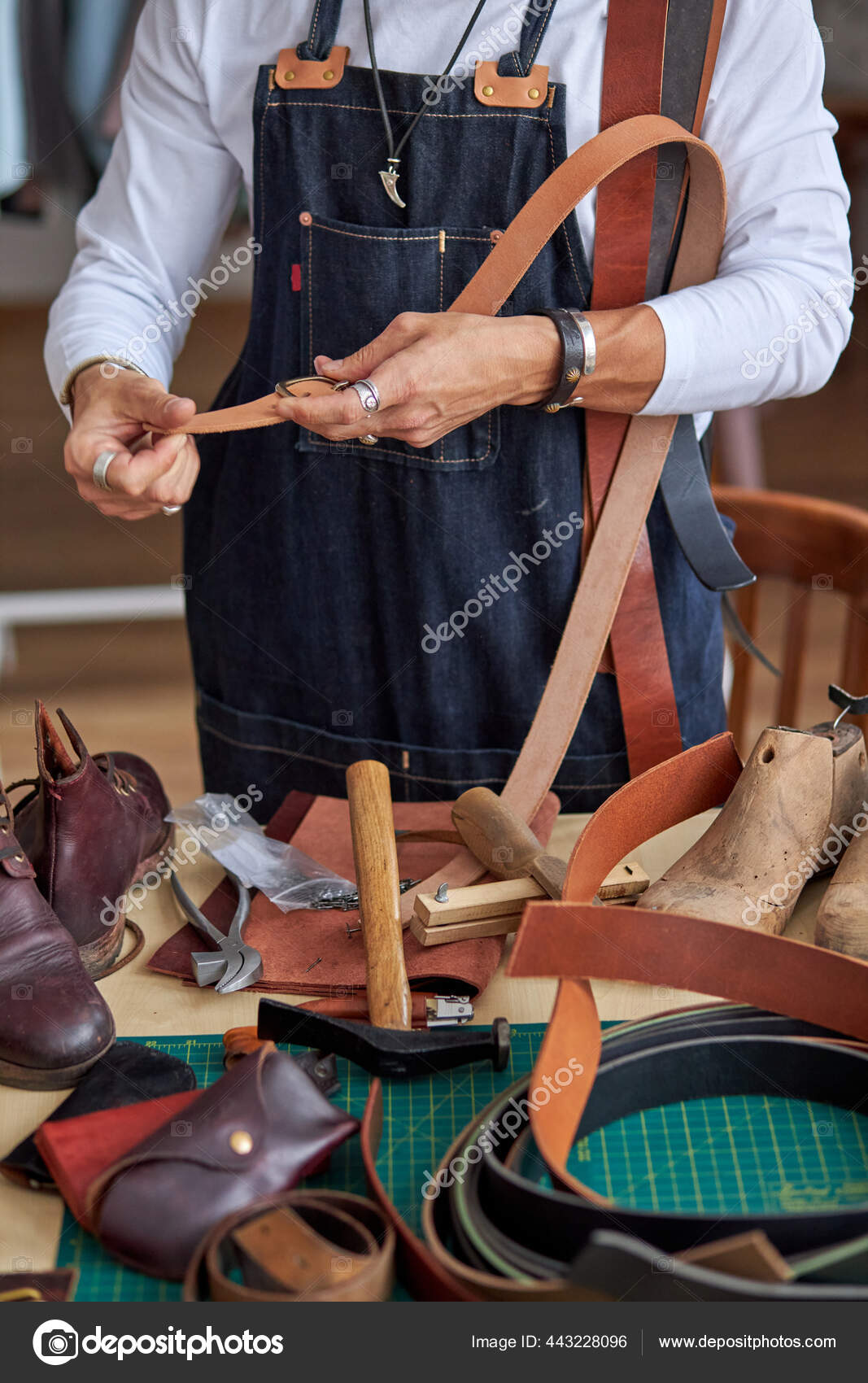 Tailor in apron working with leather belt at workshop, craftsman ...