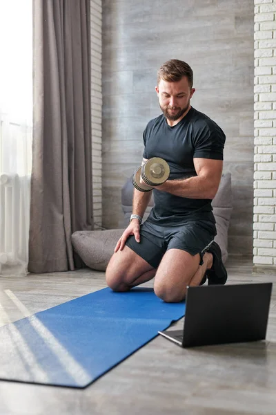 Muscular man exercising with dumbbells at home alone - Stock Image ...