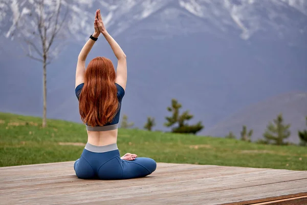 Morning Exercises in mountains landscape. Young red-haired Woman doing ...