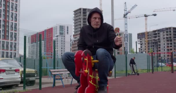 Stranger maniac in black wear offers candy to the child in playground ...