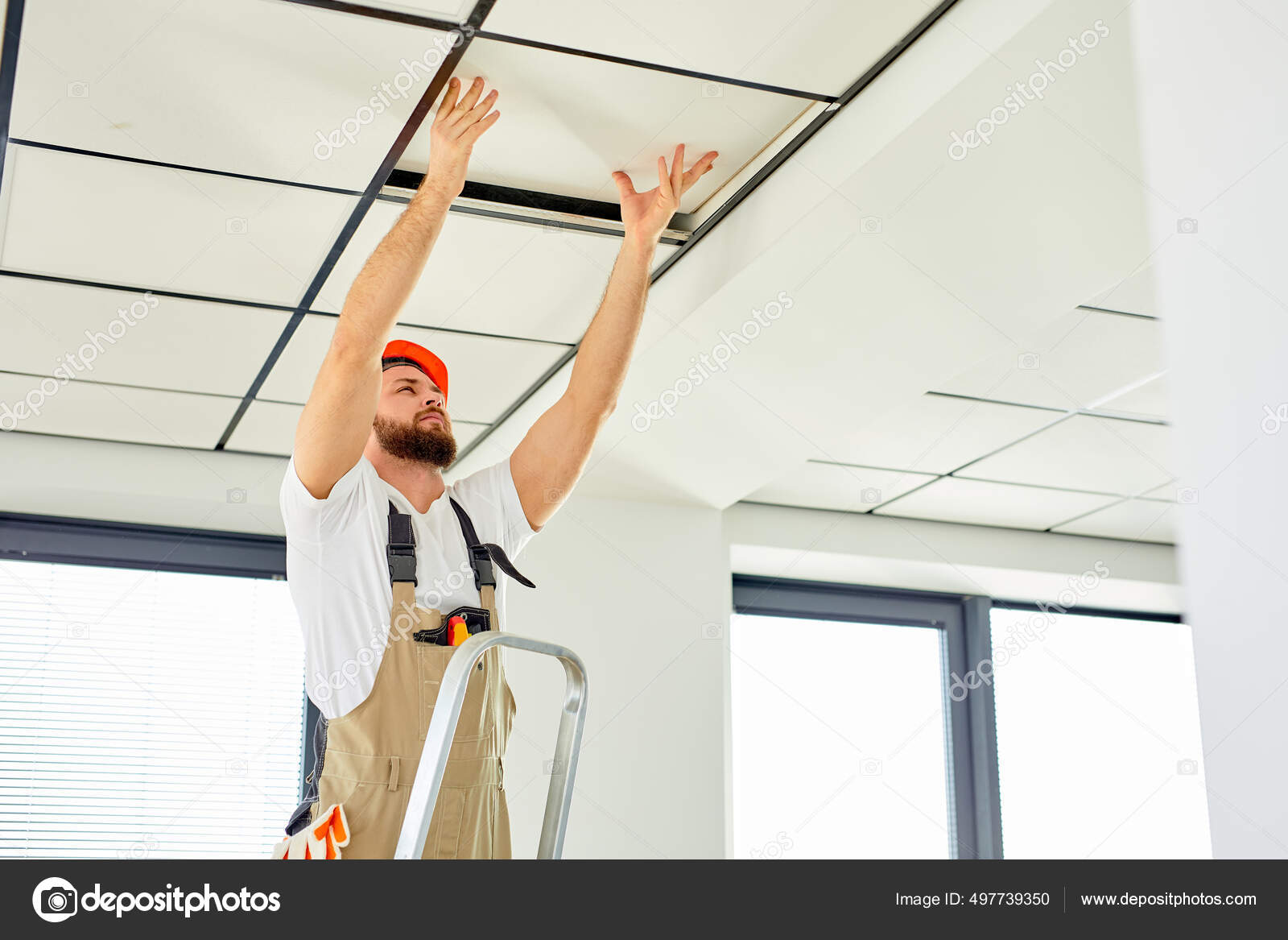 Room repair. Interior finish. young builder repairing ceiling, standing ...