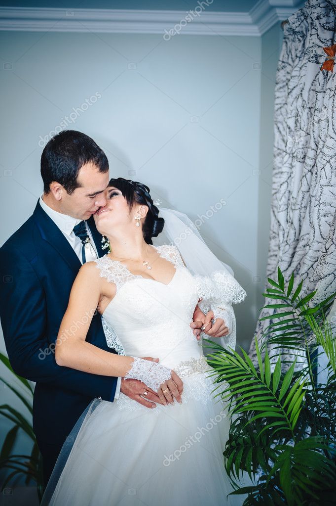 Charming bride with groom embraces and kisses on their wedding ...