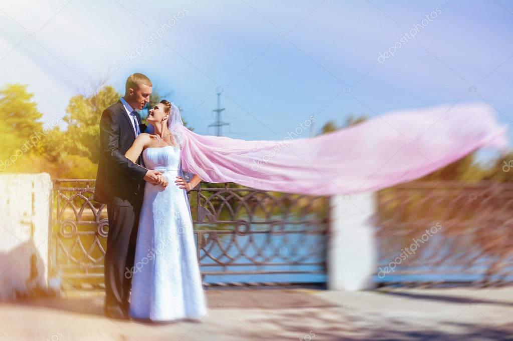 Newly married couple.wind lifting long white bridal veil. bride and ...