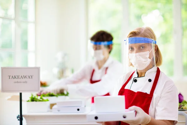 Food takeaway in restaurant in coronavirus outbreak. Cafe staff in face ...