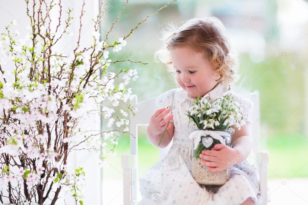 Little girl with first spring flowers at home Stock Photo by ...