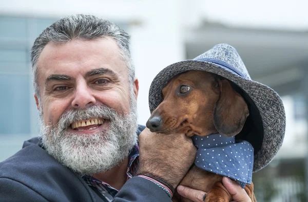 Aantrekkelijke oude man met baard en muts met hond teckel — Stockfoto ...