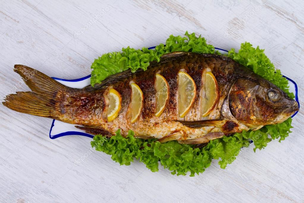 Carpa entera de pescado a la parrilla servida con ensalada y limón ...