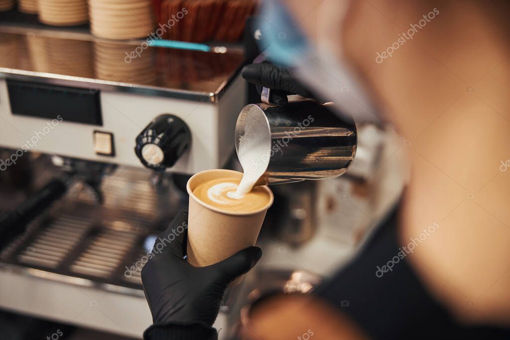 Barista hábil creando un patrón fino en la superficie del café con ...