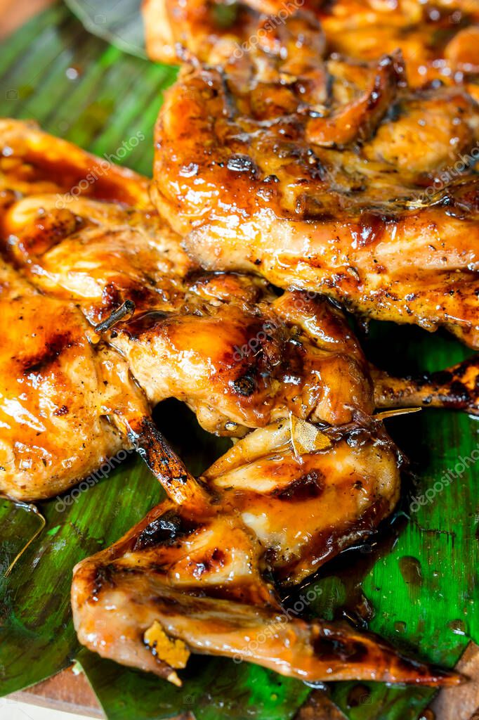 Primer plano del Pecho Inasal de Pollo (Pechuga y ala) sobre una hoja ...
