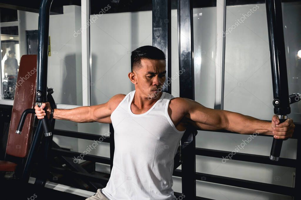 Un hombre asiático buff utiliza la máquina de la mosca del pecho en el ...