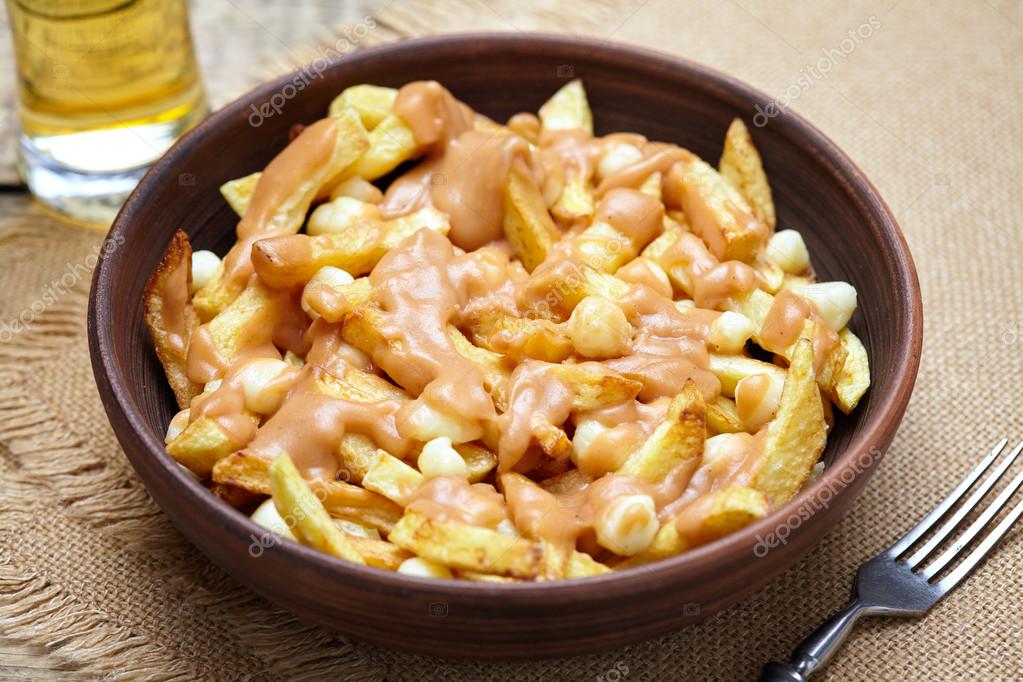 Poutine comida rápida tradicional canadiense con papas fritas, queso cuajada, salsa 2023