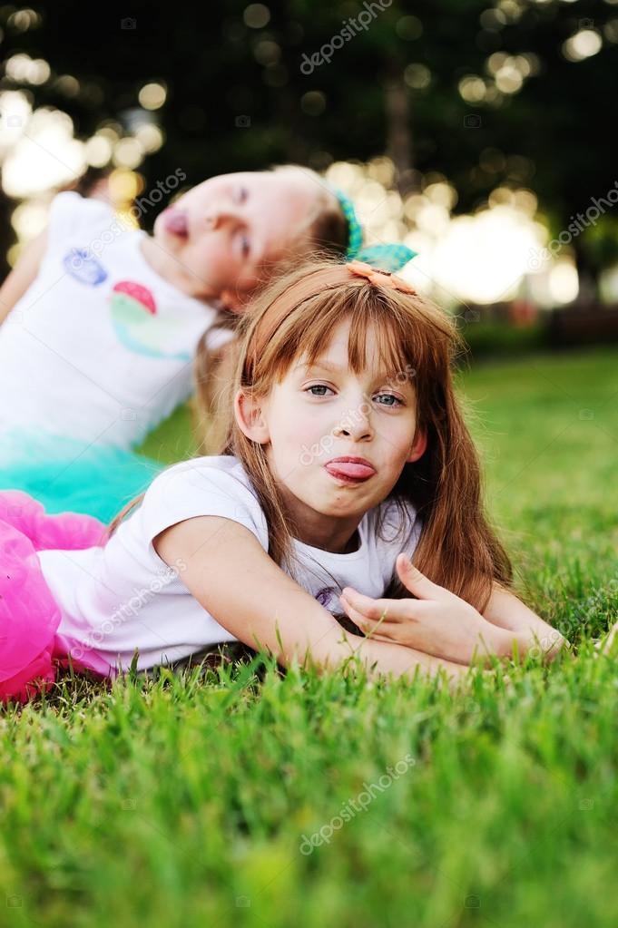 Two little girls grimace on the grass background — Stock Photo ...