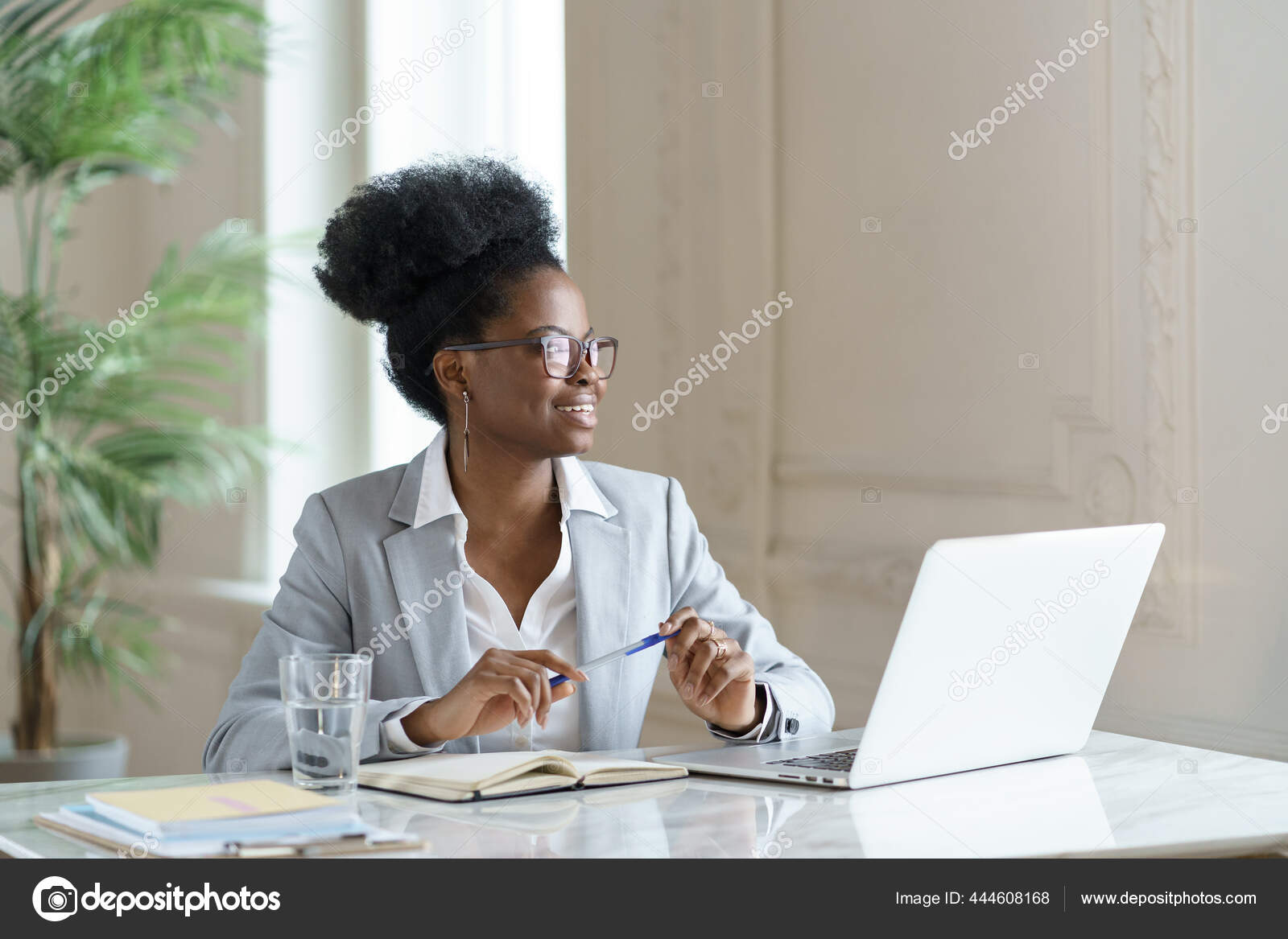Smiling Afro woman in blazer wear glasses working at laptop computer at ...