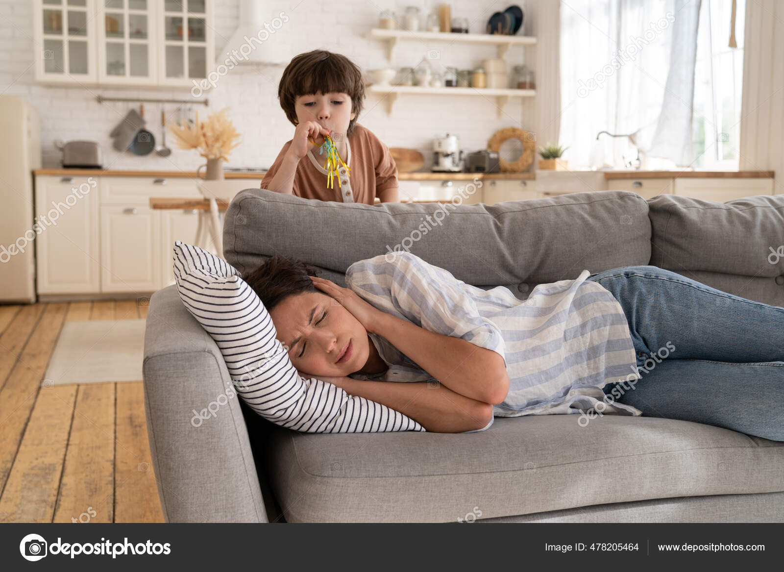 Exhausted caucasian mom lying on couch with eyes closed cover ears ...