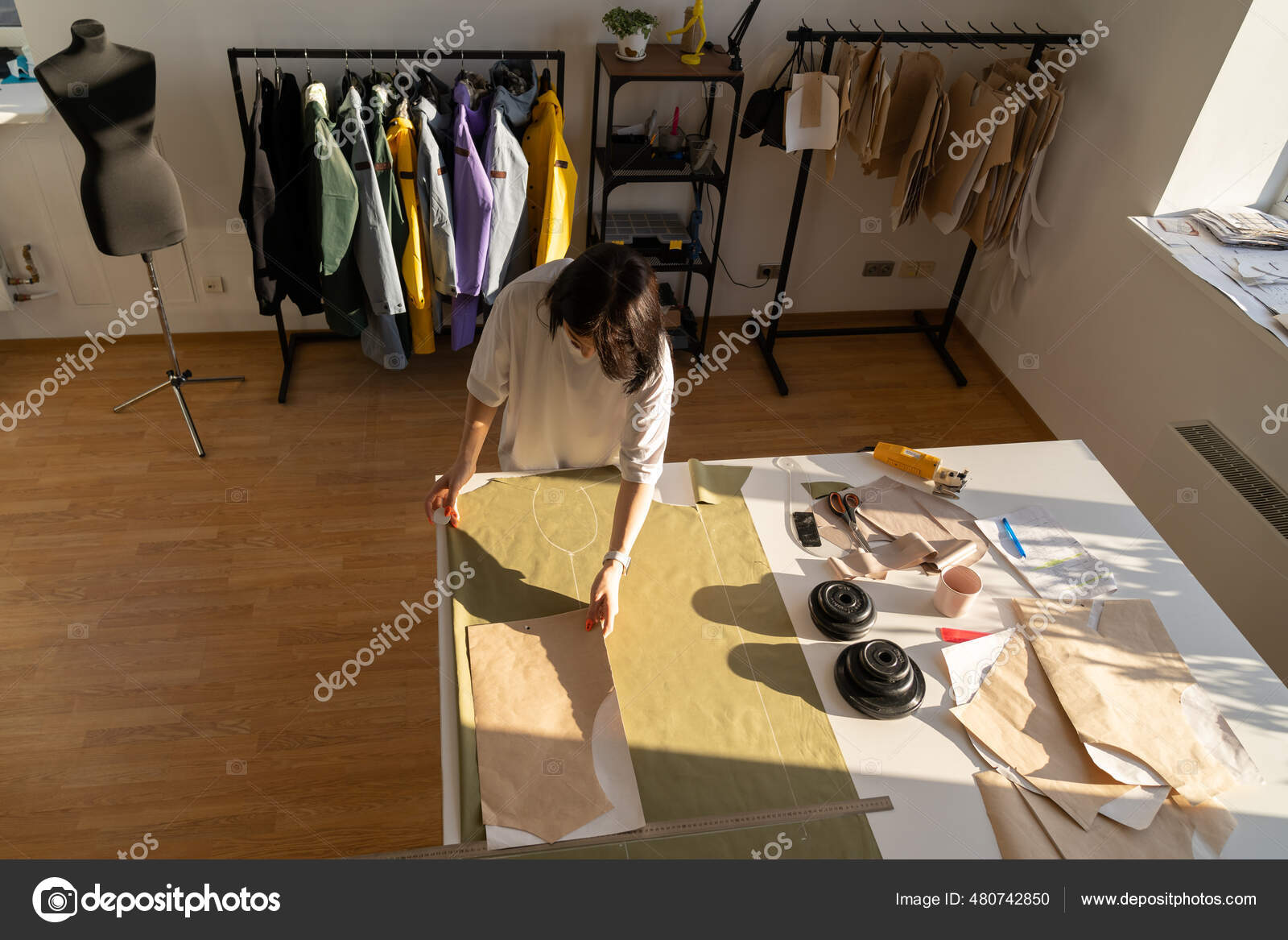 Tailor cutting textile from paper pattern. Fashion designer draft on ...