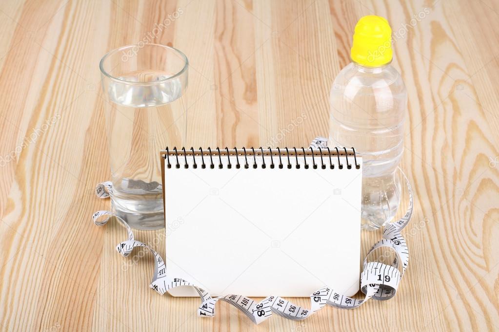 Notepad, measuring tape and water Stock Photo by ©Alexthq 85728660
