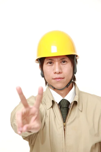 Young Japanese construction worker presenting and showing something ...
