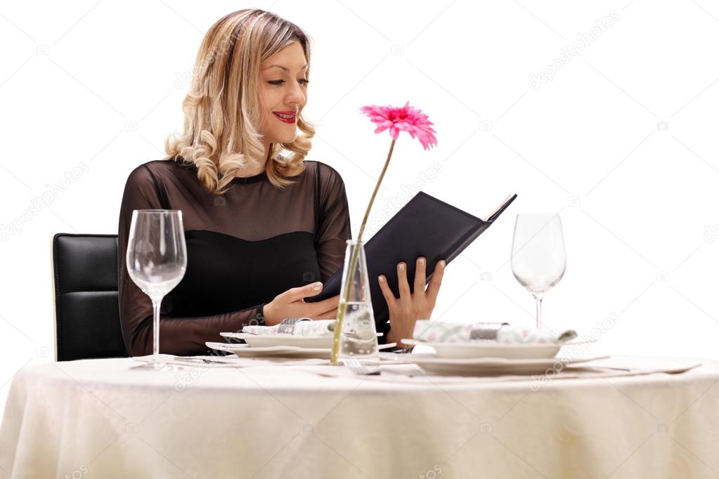 Woman at a restaurant table reading the menu — Stock Photo ...