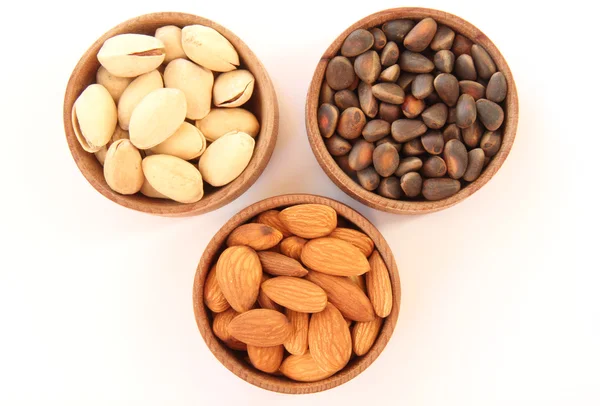 Six types of nuts in a round wooden form (almonds, hazelnuts, pine nuts ...