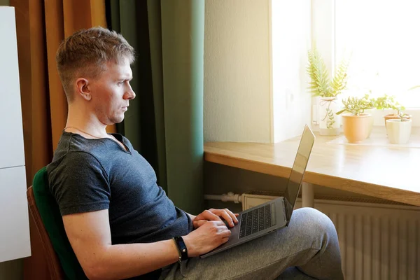 A young male programmer works remotely from home in home clothes. Using ...
