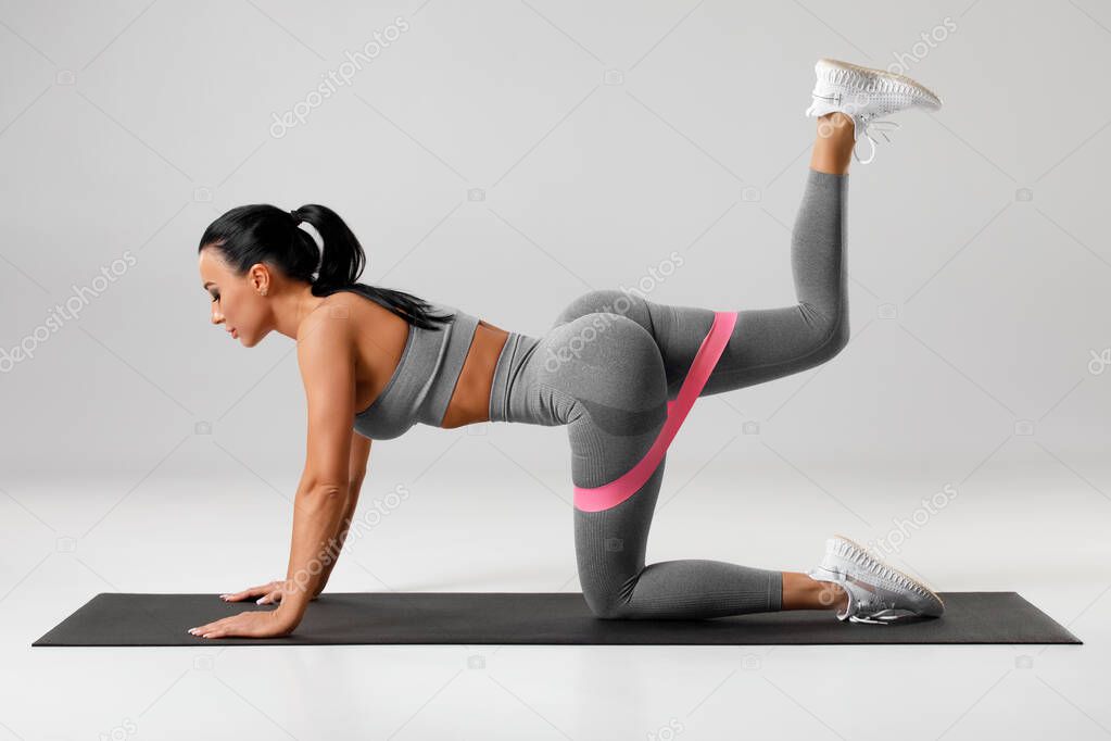 Chica atlética haciendo ejercicio de kickback para glúteos con banda de ...