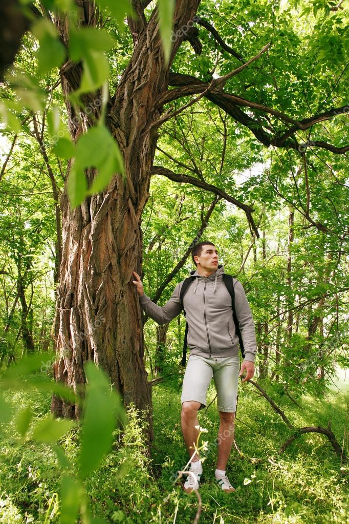 Joven excursionista con mochila caminando en el bosque de verano ...