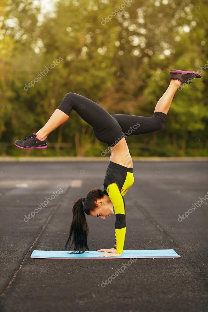 Mujer atlética delgada haciendo ejercicio handstand en el estadio ...