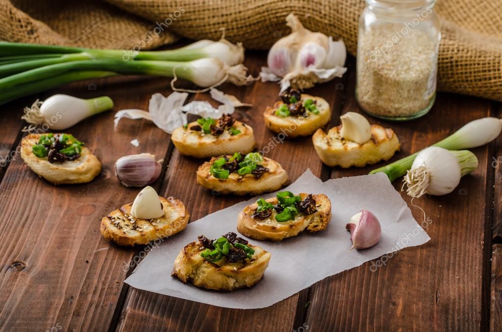 Mini toasts with garlic and dried tomato Stock Photo by ©Peteer 73621451