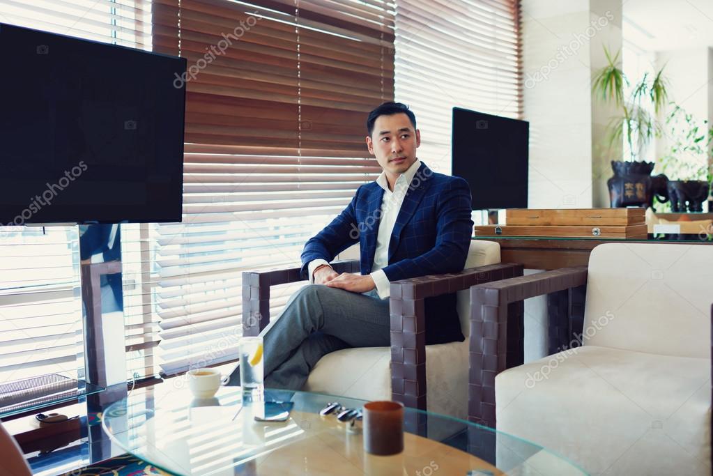 Young male CEO is sitting near screens with copy space for your content ...