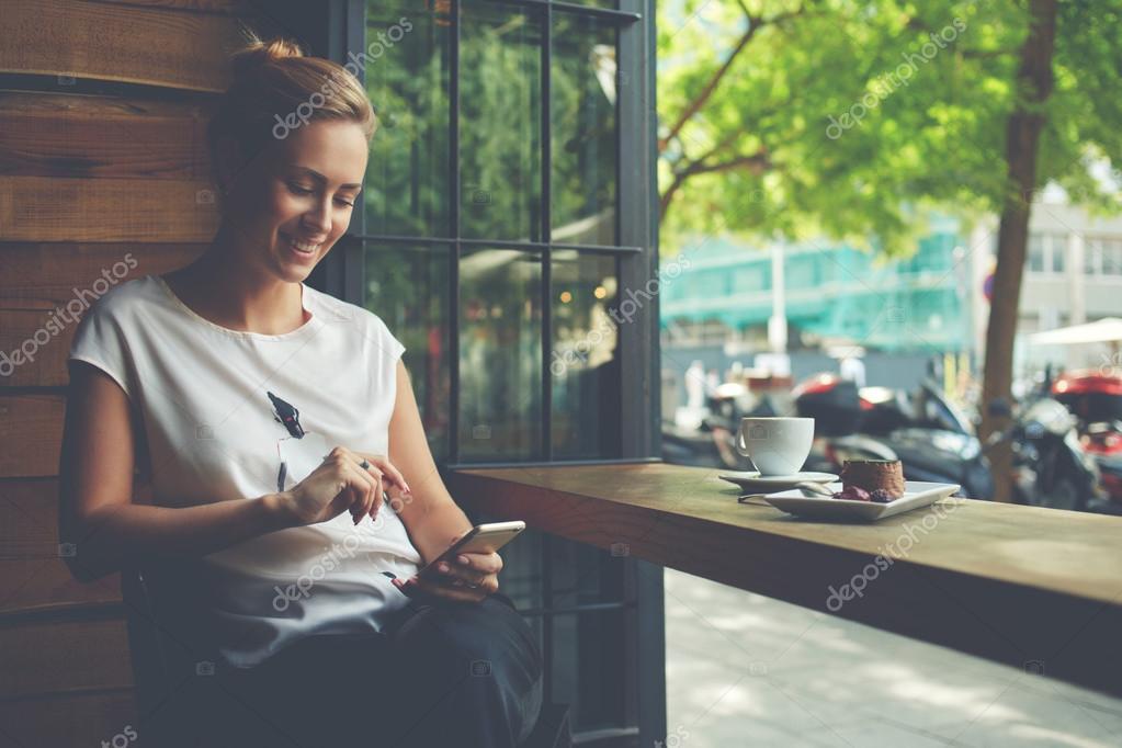Happy Caucasian female watching her photos on cell telephone while ...