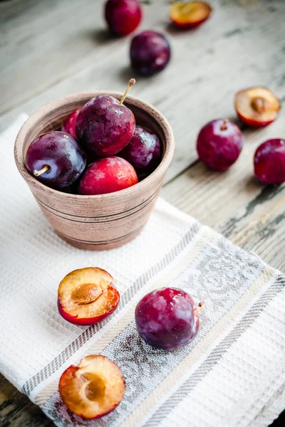 Fresh pink plum in pottery on gray wooden table, rustic - Stock Image ...