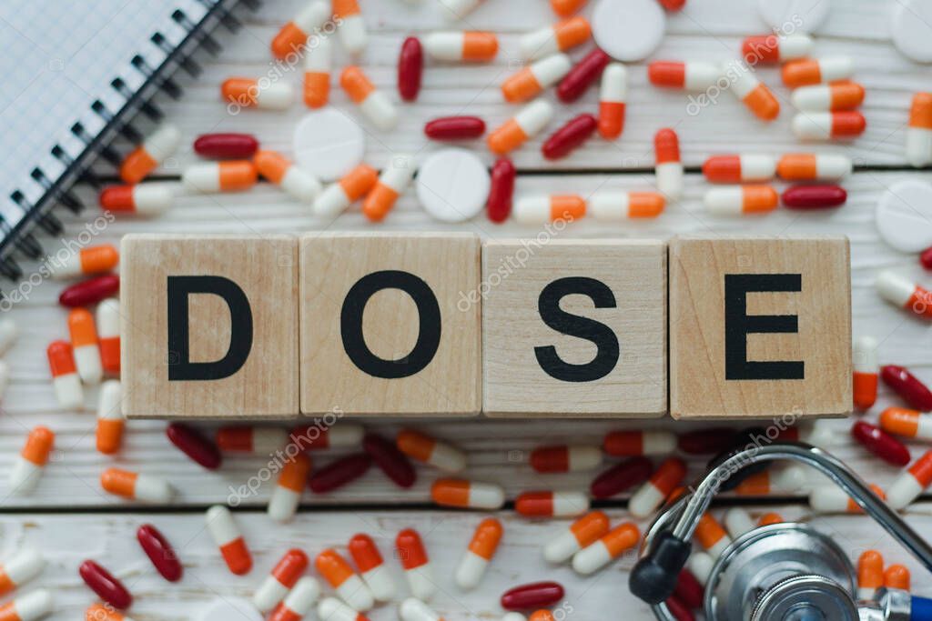 La palabra DOSE está hecha de cubos de madera sobre un fondo blanco con ...