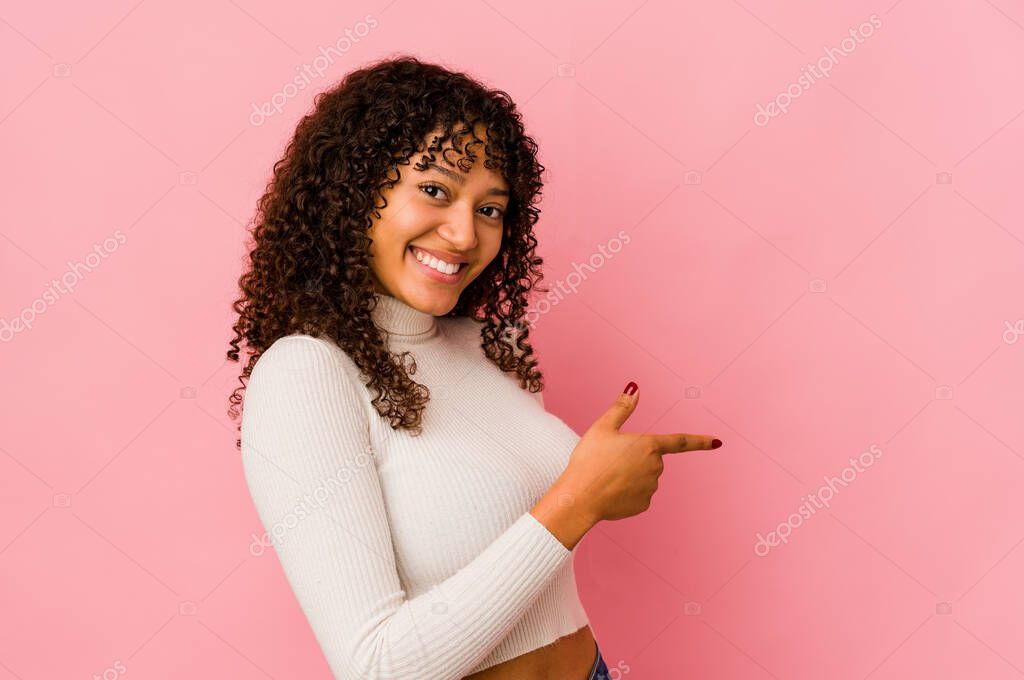 Joven afroamericana afro mujer aislada sonriendo y señalando a un lado ...