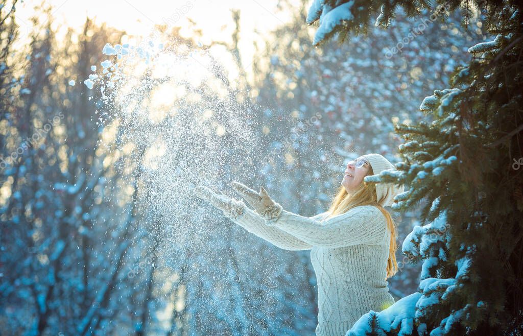 La mujer feliz juega con la nieve en el día soleado invernal. A la ...